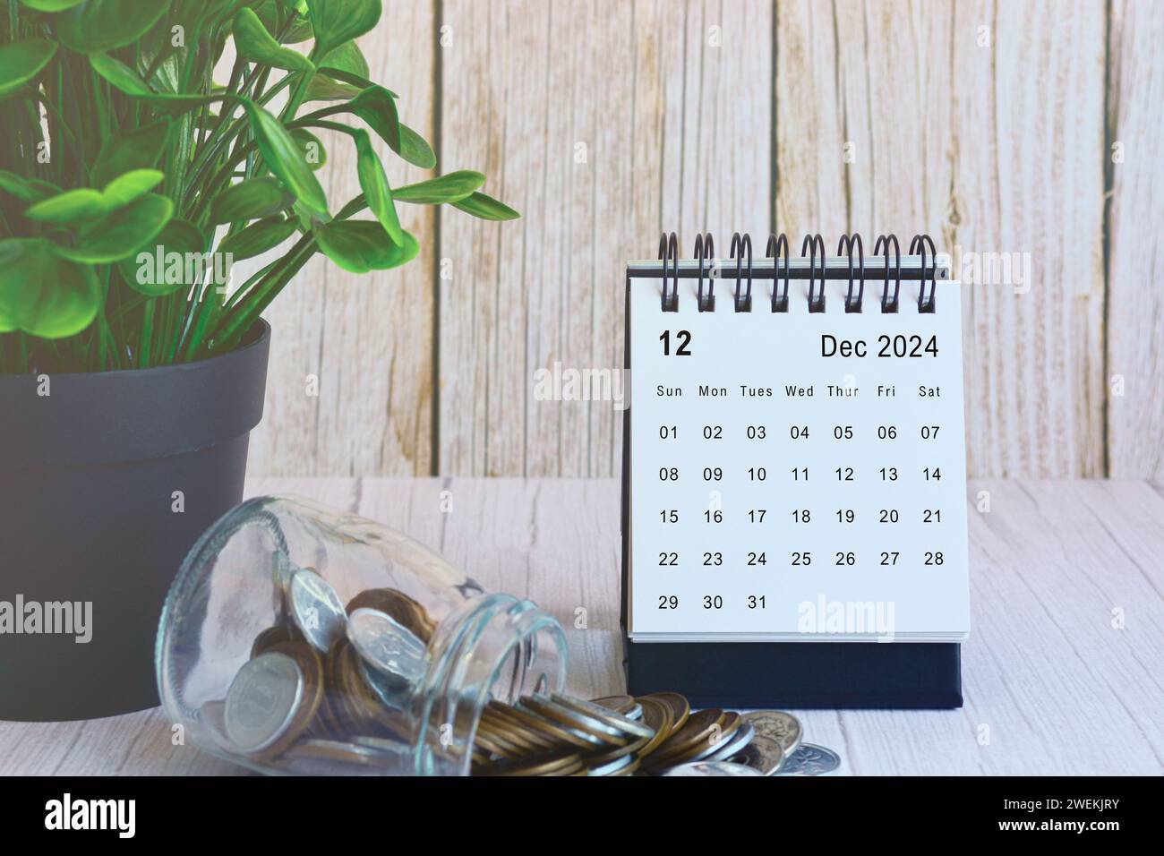 December 2024 desk calendar with stack of coins and potted plant on ...