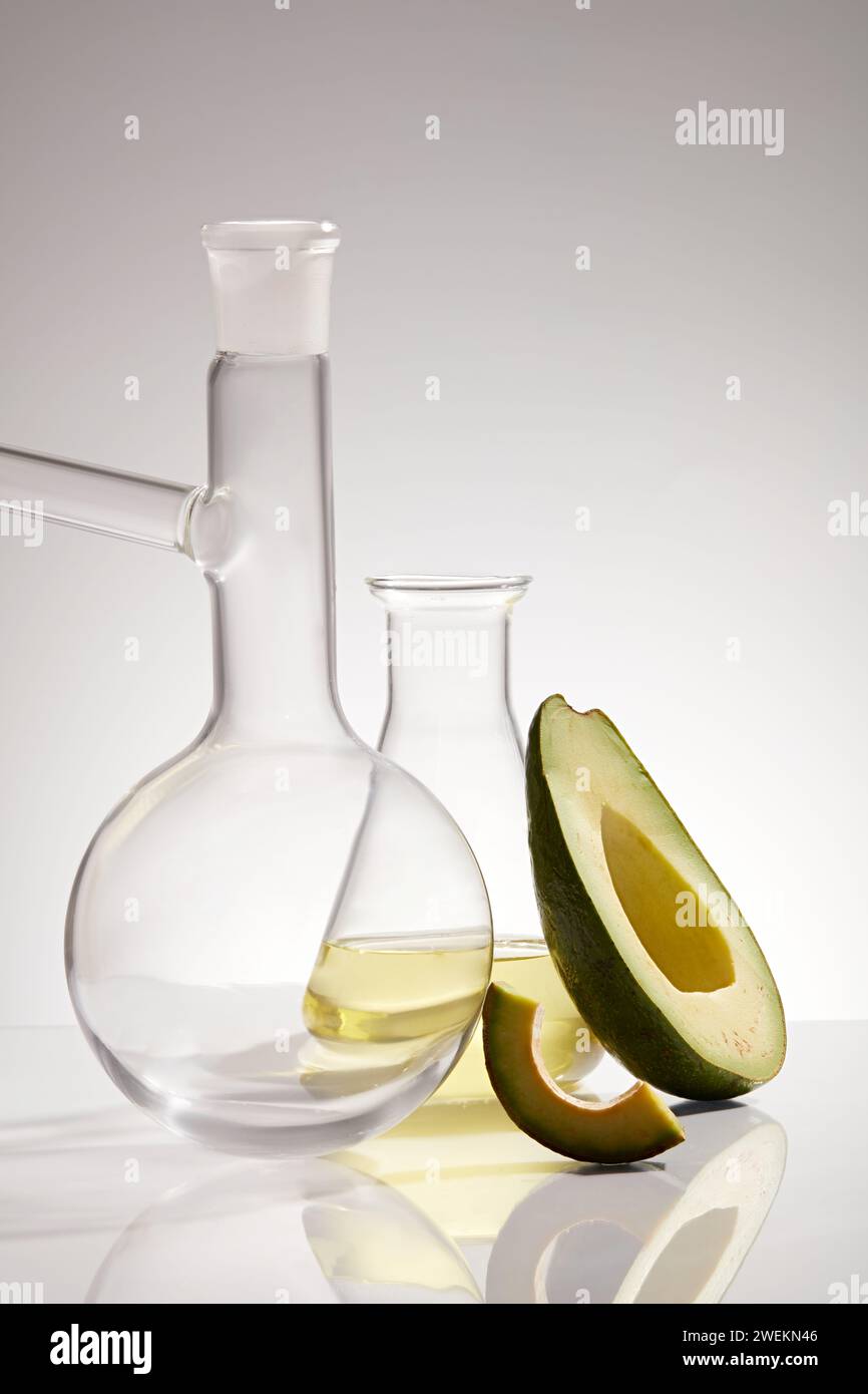 Front view of lab glassware containing essential oil and fresh avocado ...