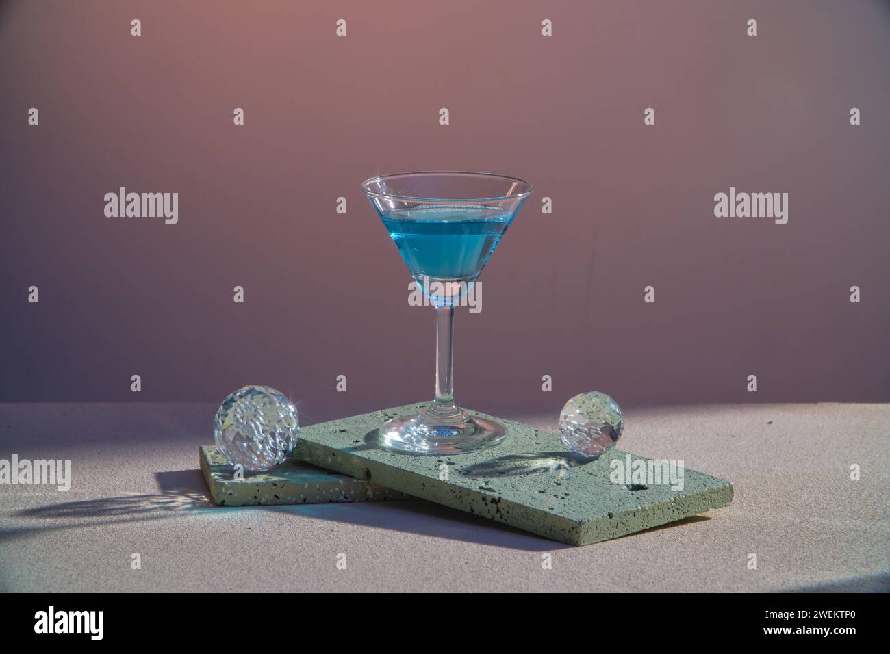 Blue cocktail drink in a glass with transparent ball placed on gray ...