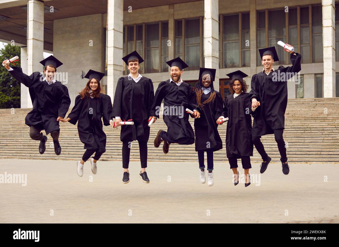 Happy smiling graduates students classmates jumping in black graduate ...