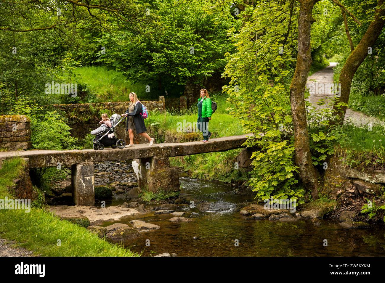 UK, England, Lancashire, Colne, Wycoller, family crossing Clam Bridge ...