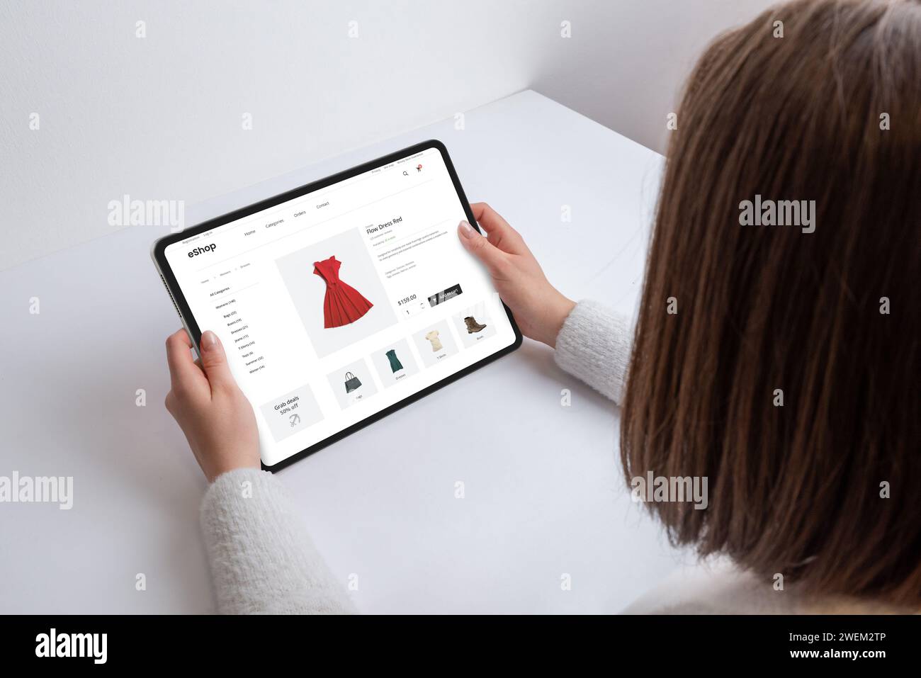 Woman holds tablet with an e-commerce webpage, searching for a red ...