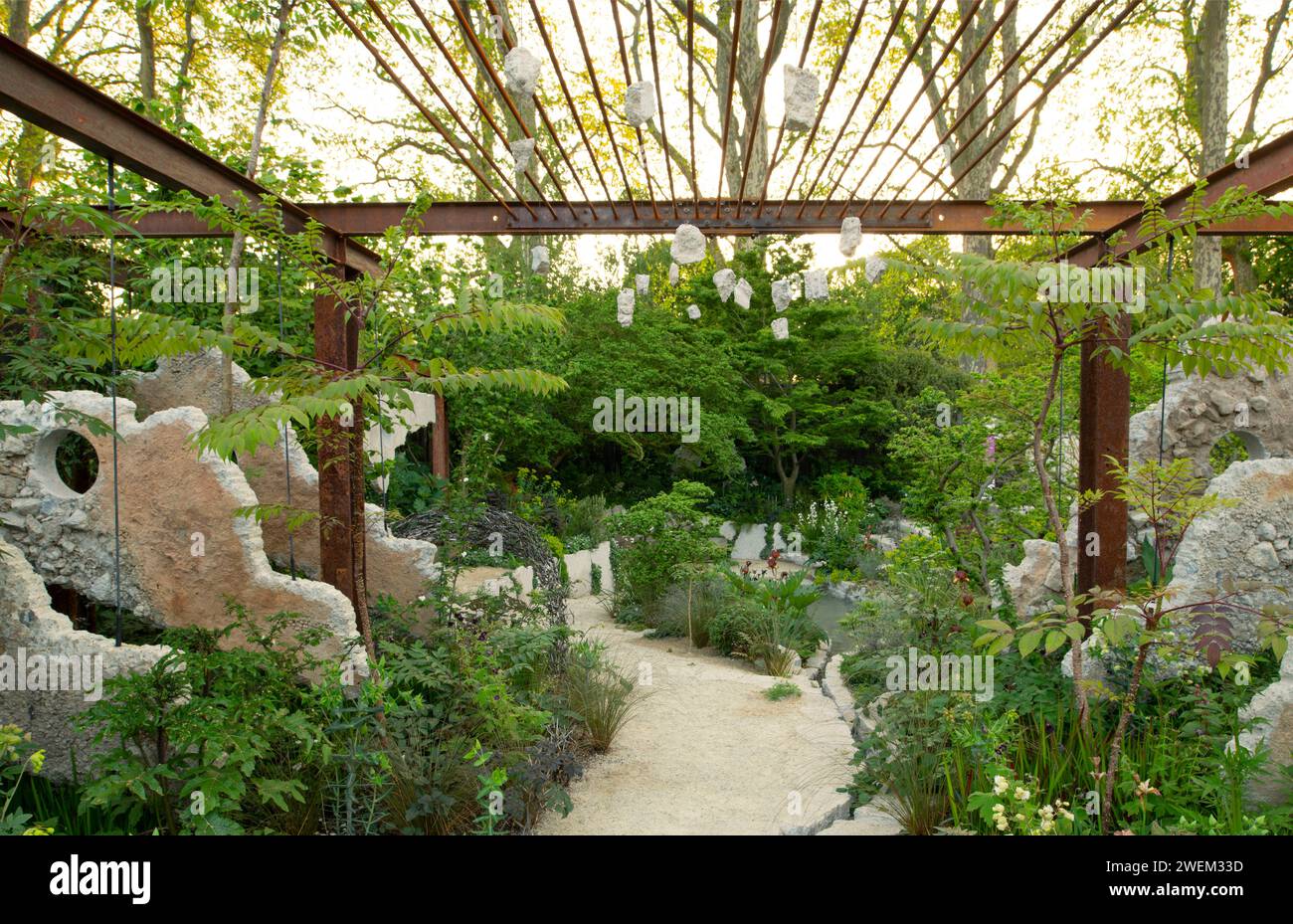 Concrete panels and a metal grid frame a pathway through perennials in ...