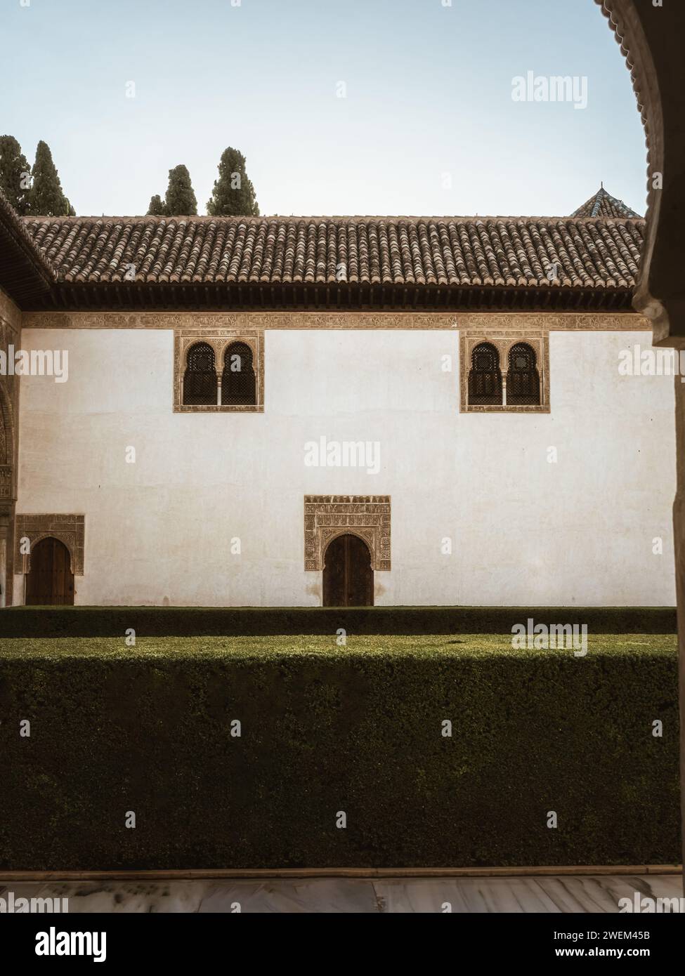 Ornate doors and windows on a white wall in a courtyard in the Alhambra, Granada, Andalusia ...