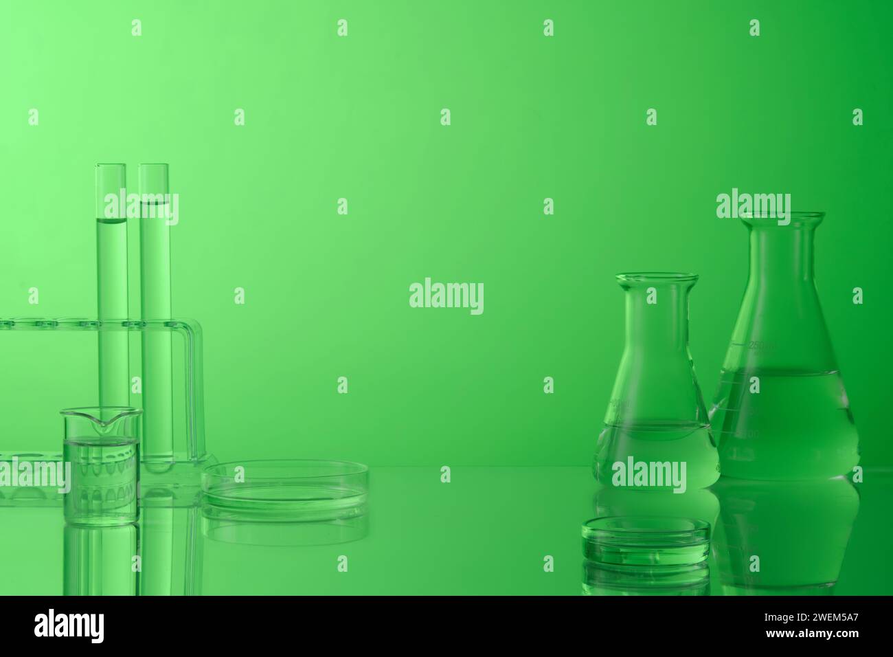 Laboratory glassware with liquid on green background. Test tubes ...