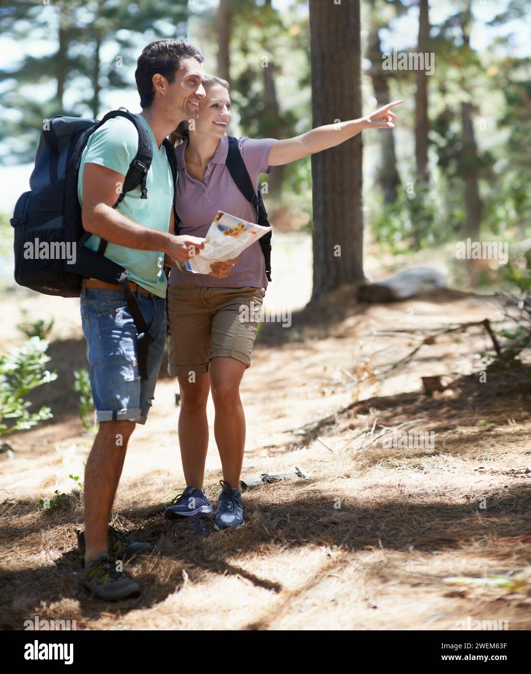 Couple, trekking in nature and map for direction, documents guide or ...