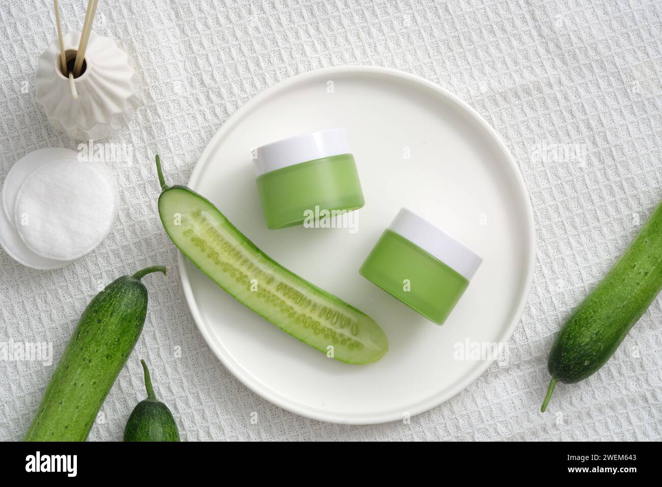 Top view of cream jars and cucumber slices on round dishes, cotton pads ...