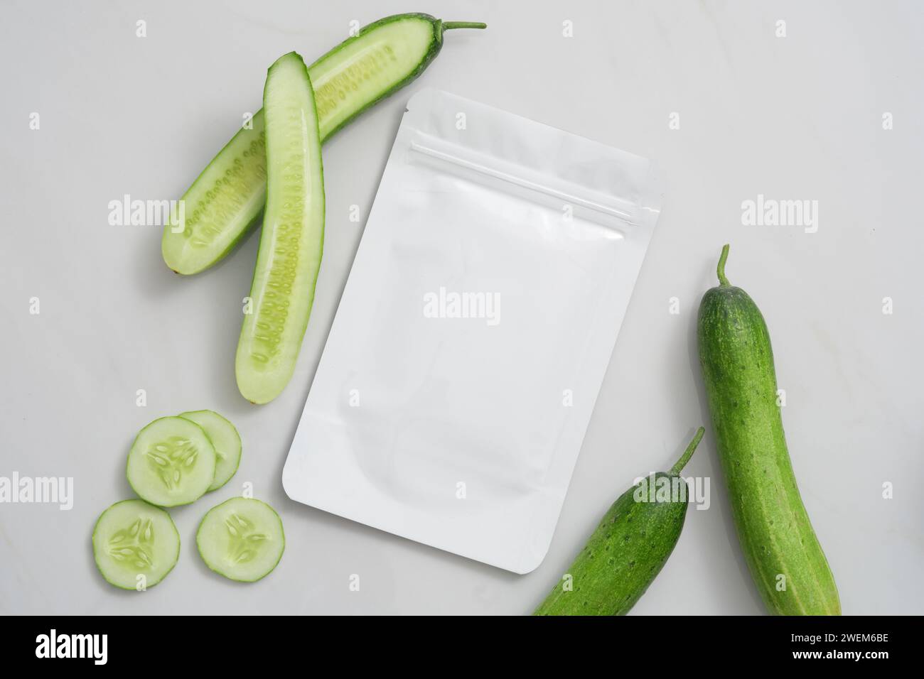 Mockup of a facial sheet mask package with fresh cucumber slices on ...