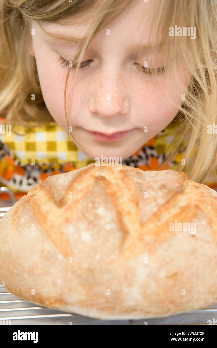 Young Girl Smelling a Loaf of Bread Stock Photo - Alamy