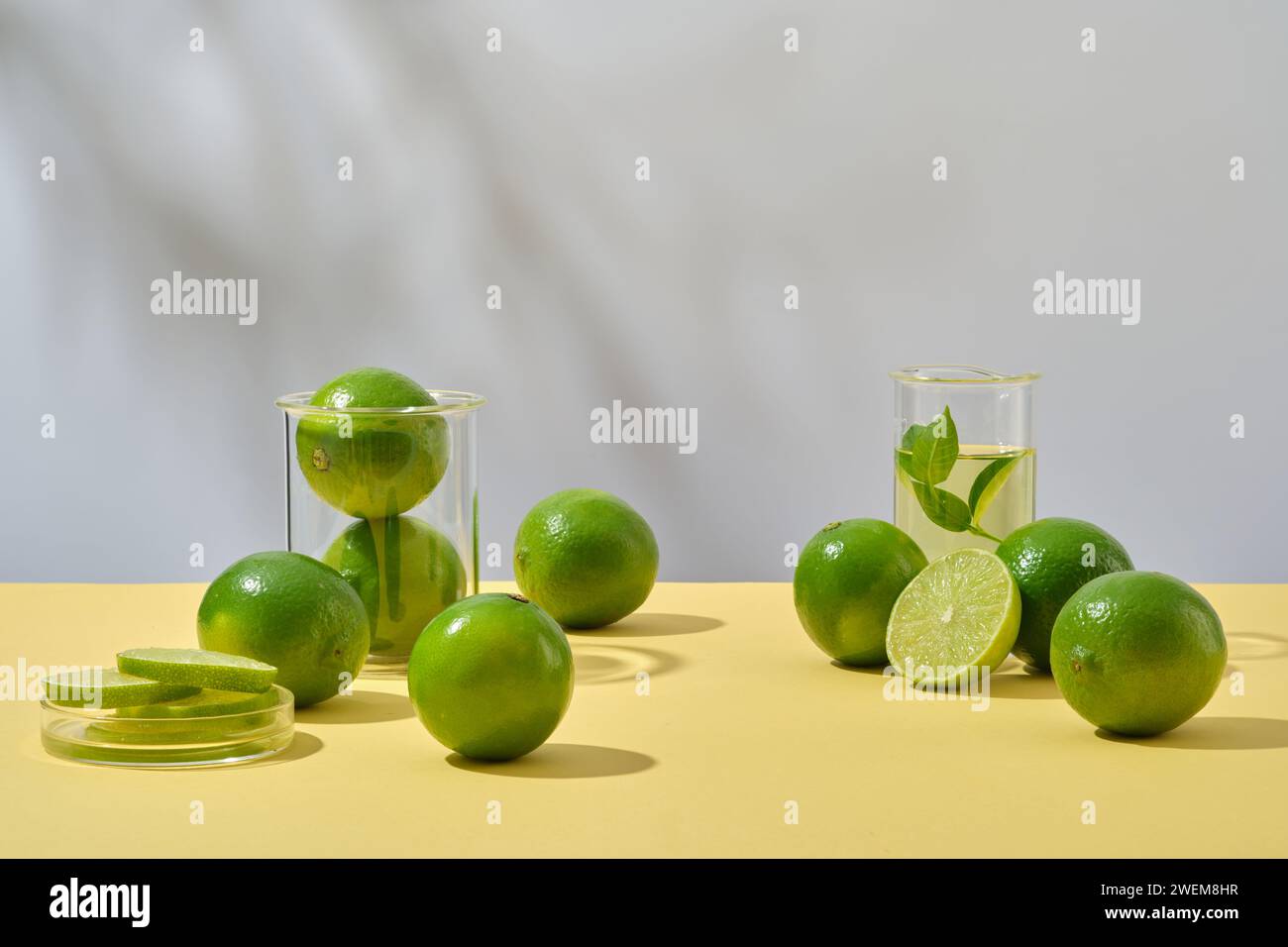 Front view of fresh limes and lab glassware decorated on white ...