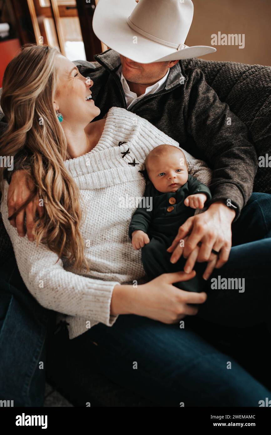 Newborn baby boy cuddled by mom and dad on the couch Stock Photo - Alamy
