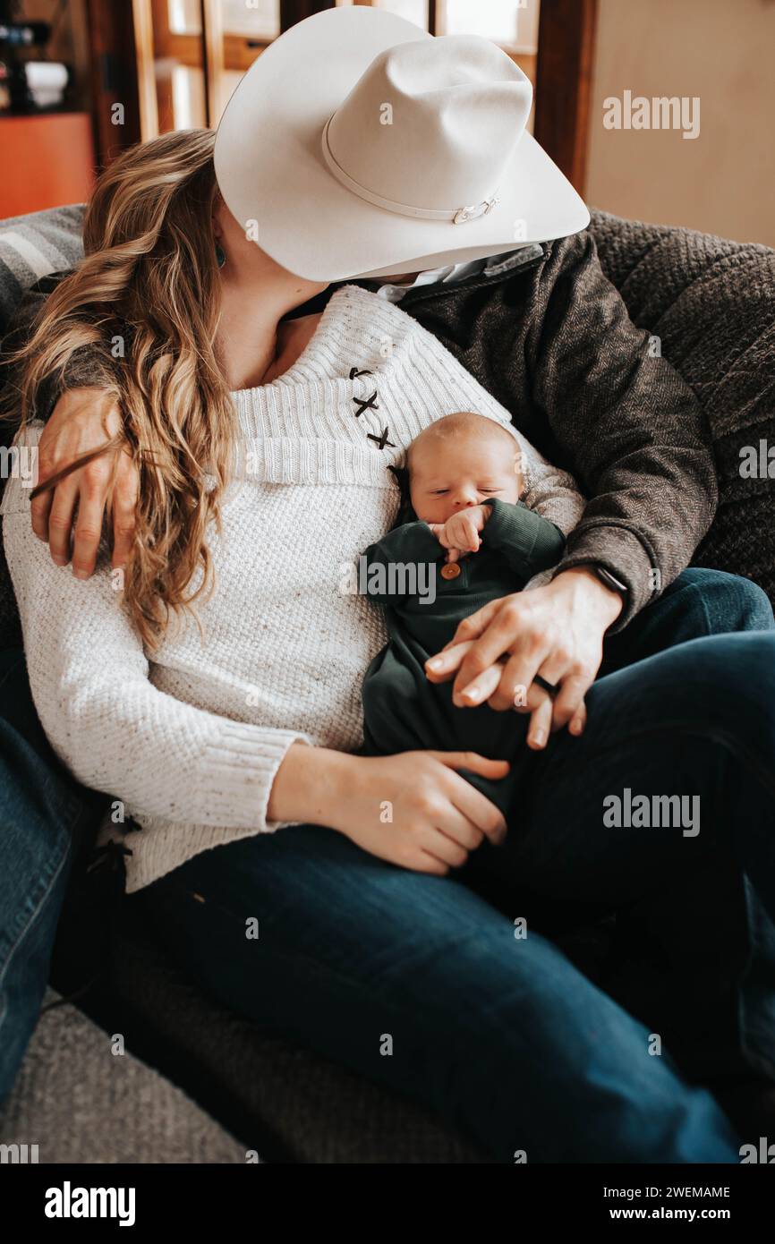 Newborn baby boy cuddles with parents on couch, kissing Stock Photo - Alamy