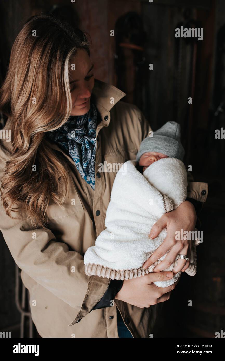 Mom cuddles new baby boy in a blanket outside the horse barn Stock ...