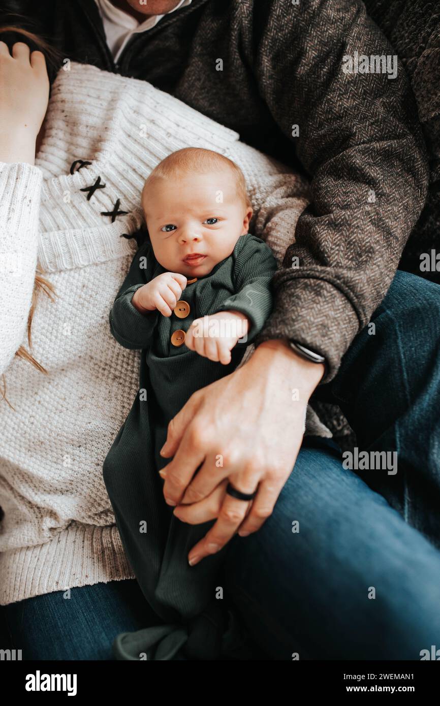Newborn baby boy cuddled by mom and dad on the couch Stock Photo - Alamy