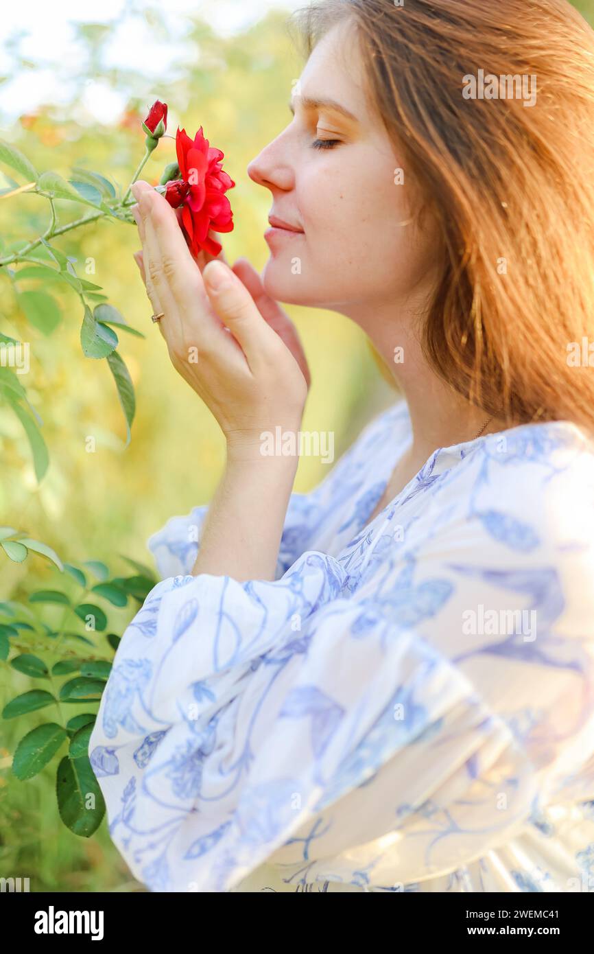 Beautiful young girl smelling a red rose Stock Photo - Alamy