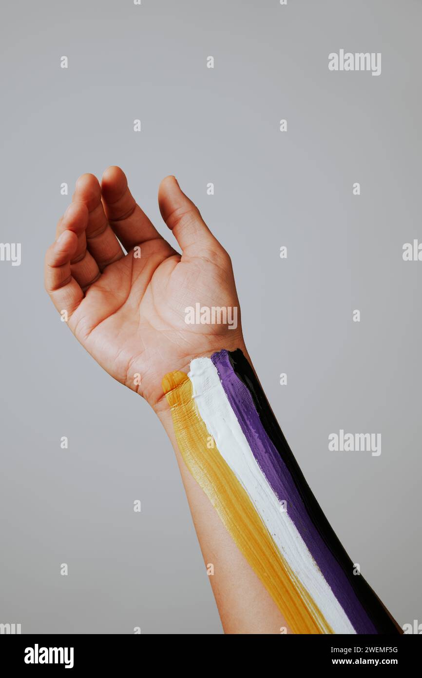 the arm of a person with a non-binary pride flag painted on it, in ...