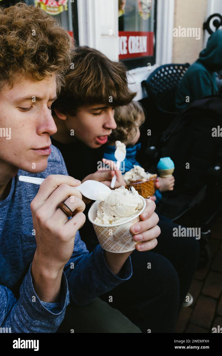 Family eats ice cream together on bench outside shop Stock Photo - Alamy