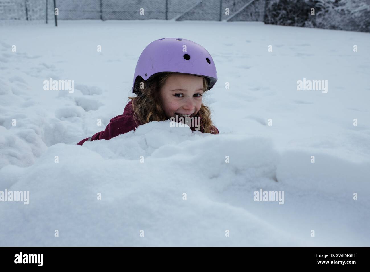 girl hiding in the snow whilst ice skating outdoors Stock Photo - Alamy