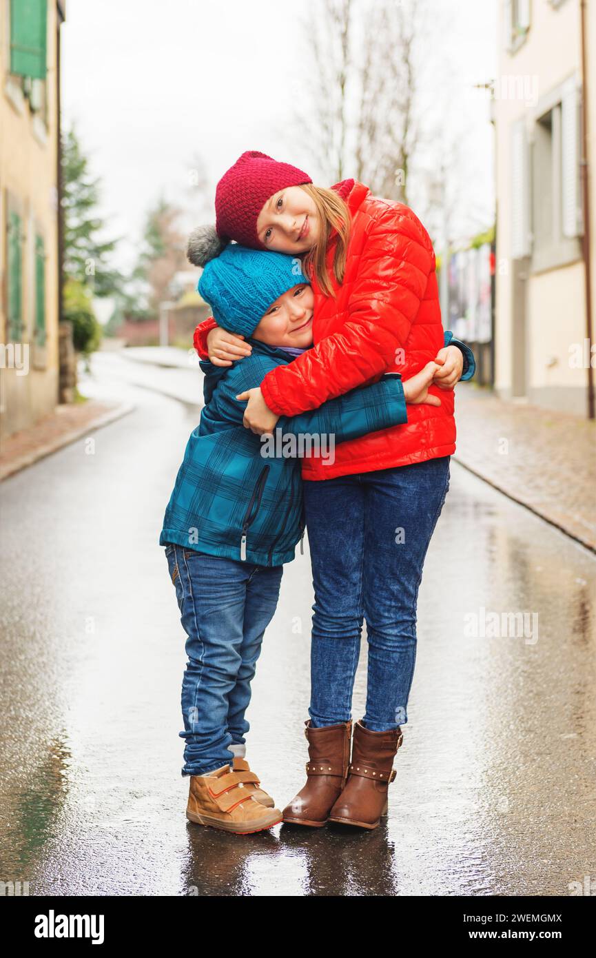 Big sister giving a hug to her small brother, kids wearing bright warm ...
