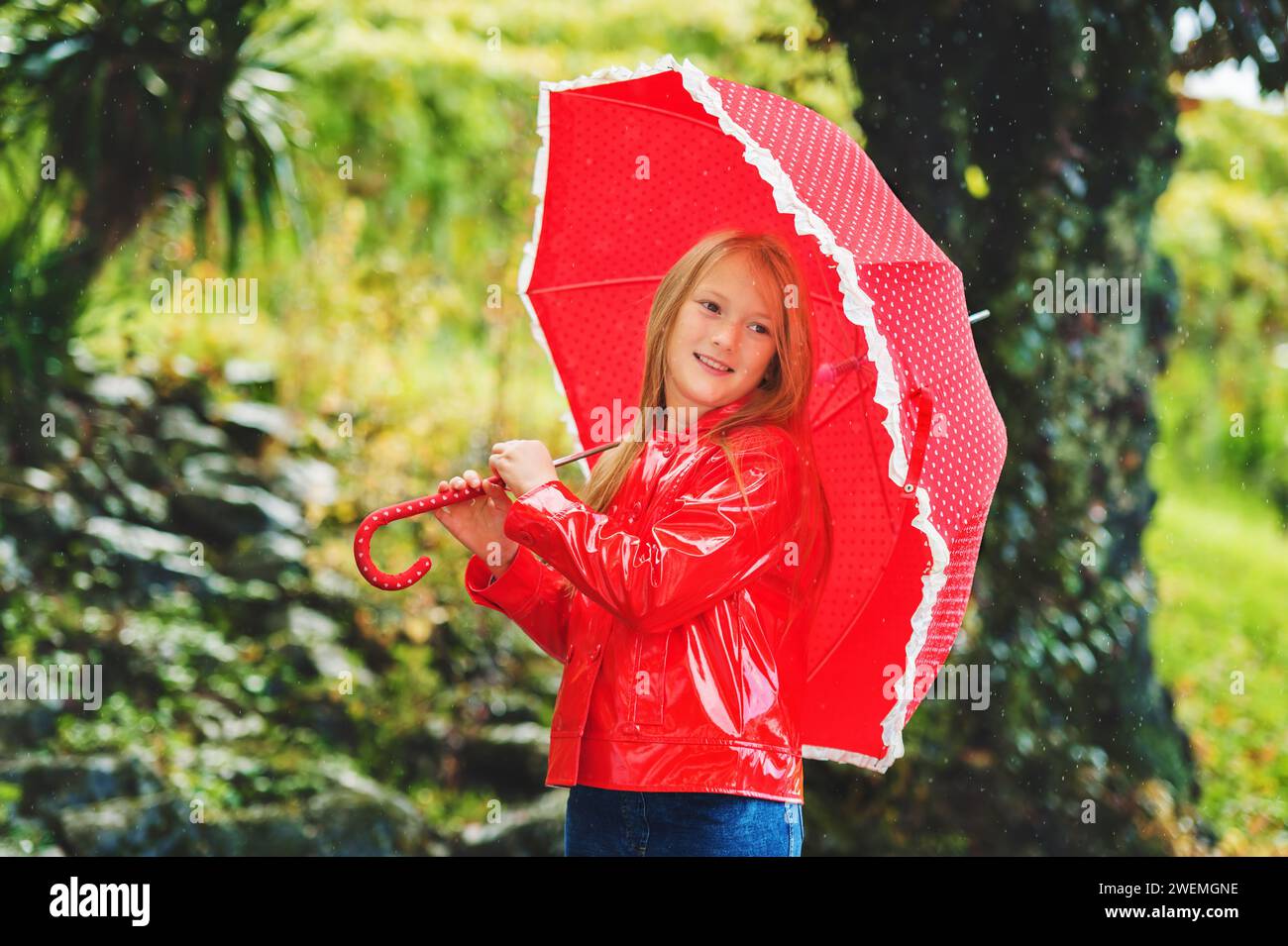 Adorable little 9 year old girl playing under the rain in the park ...