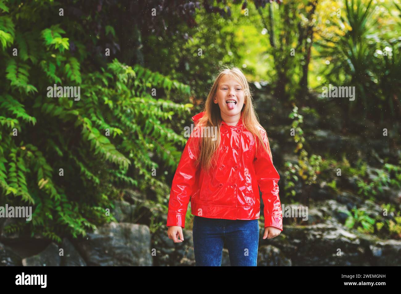 Adorable little 9 year old girl playing under the rain in the park ...