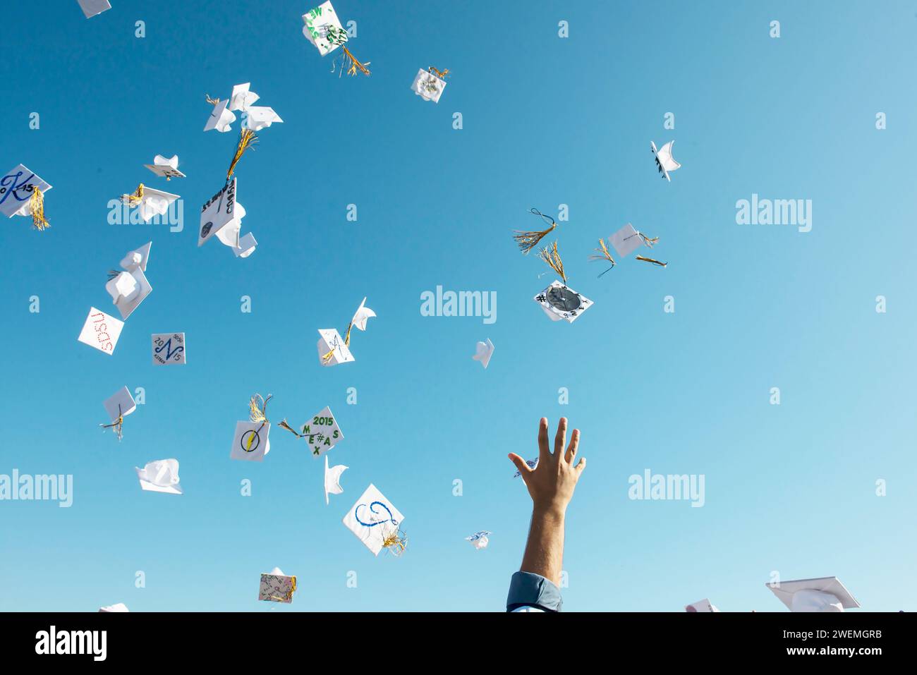 Male Hand Reaching to Sky with Graduation Caps in the Back Stock Photo ...
