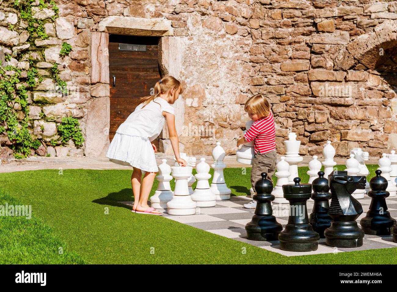 Two little kids playing giant chess outdoors Stock Photo - Alamy