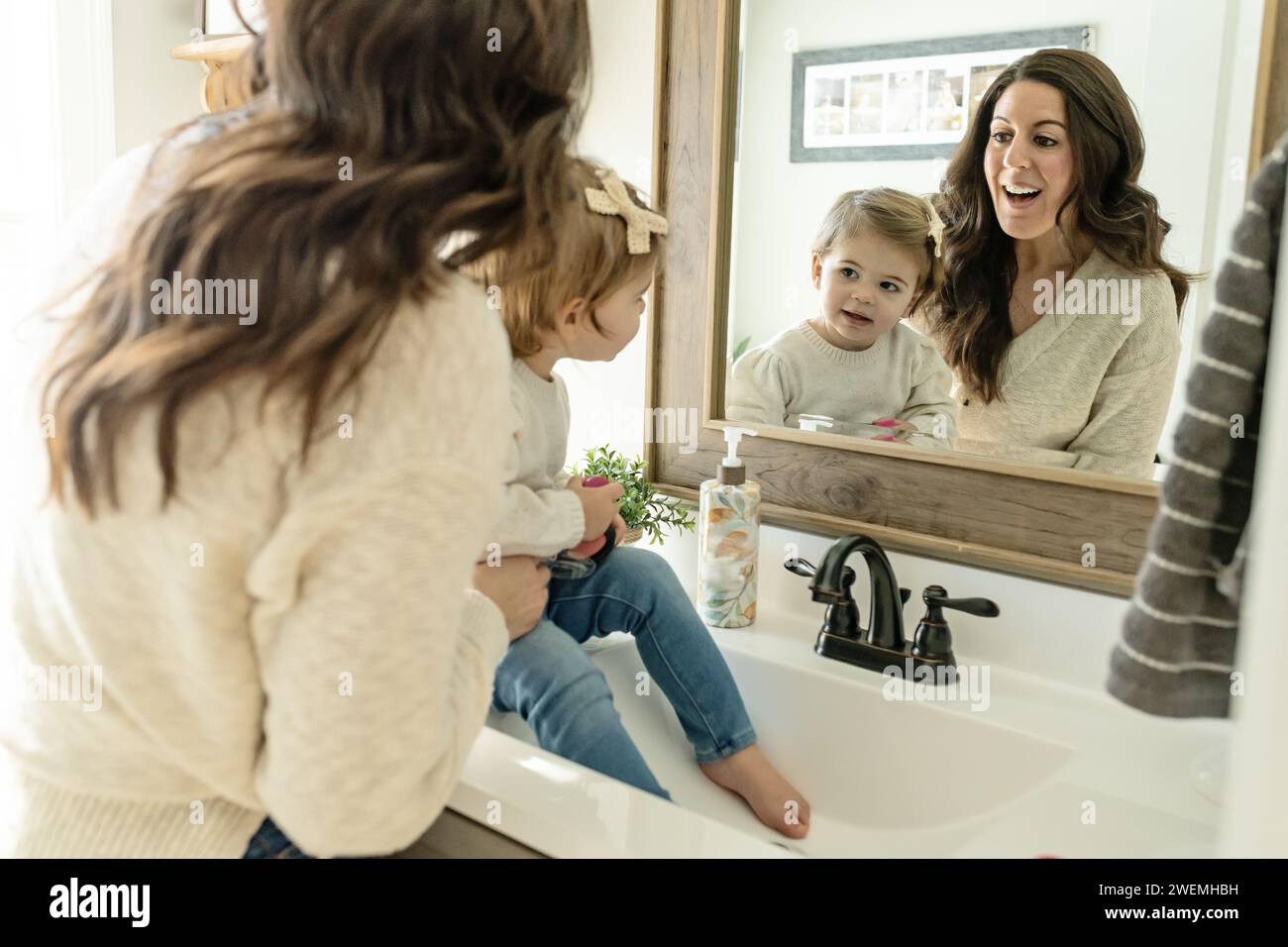 Mother and Daughter looking at Reflection in Mirror Stock Photo - Alamy
