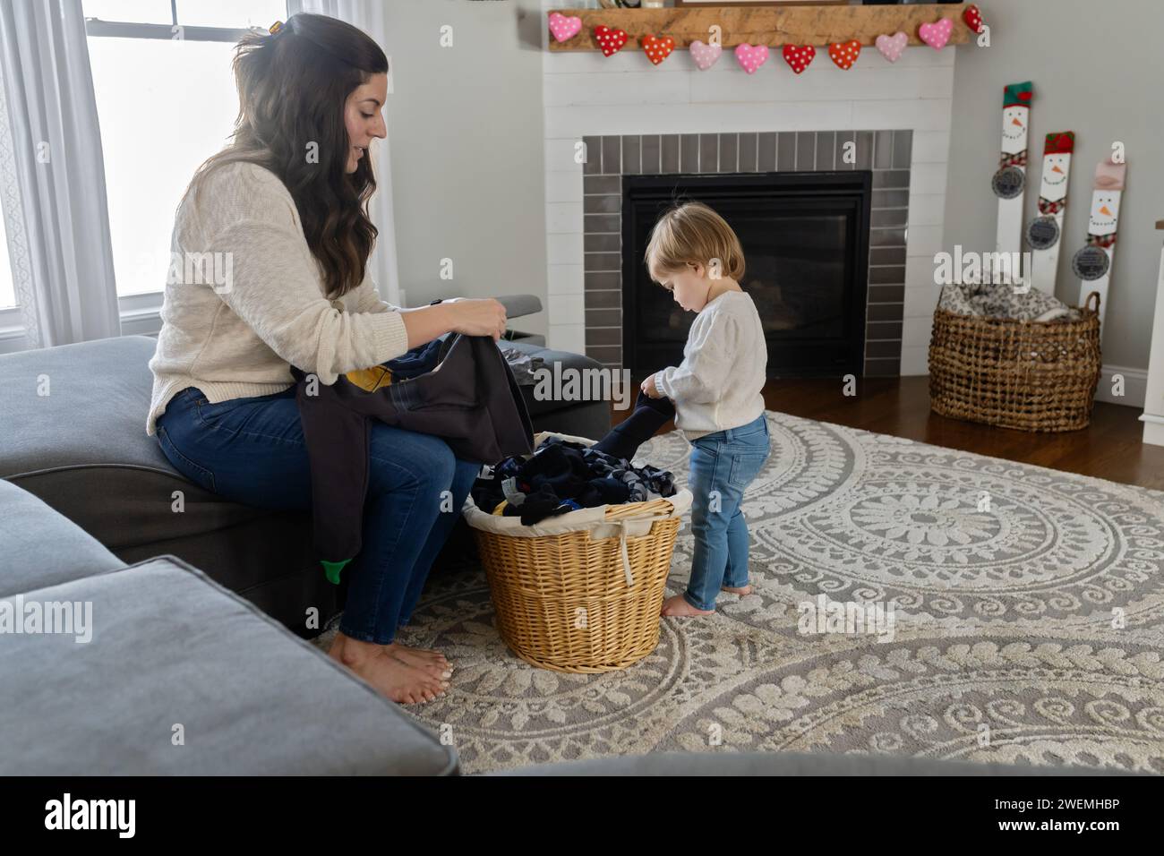 Woman folds laundry while her daughter tries to help Stock Photo - Alamy