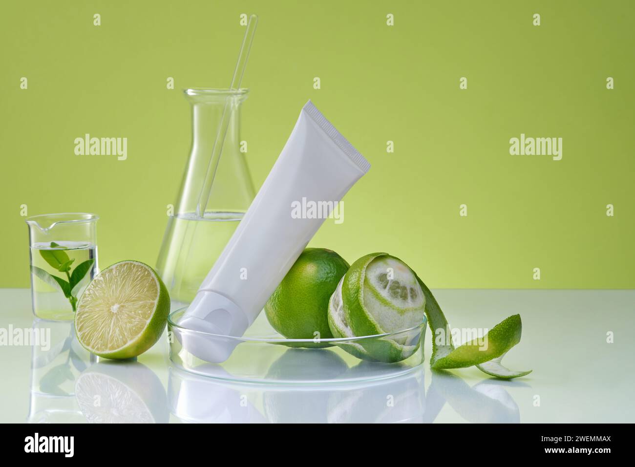 Front view of a white plastic tube unlabeled, fresh limes and lab ...