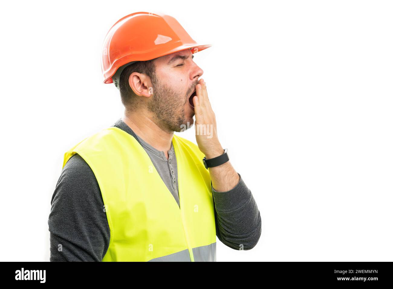 Tired adult male constructor covering mouth as yawning sleepy wearing ...