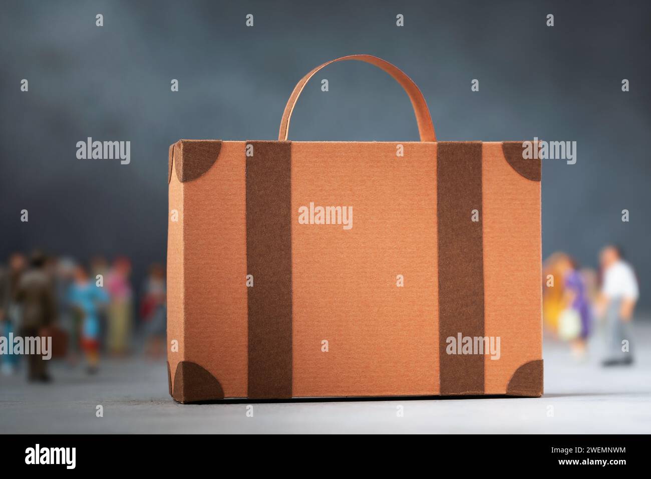 Cardboard suitcase and out of focus plastic toy men on an abstract ...