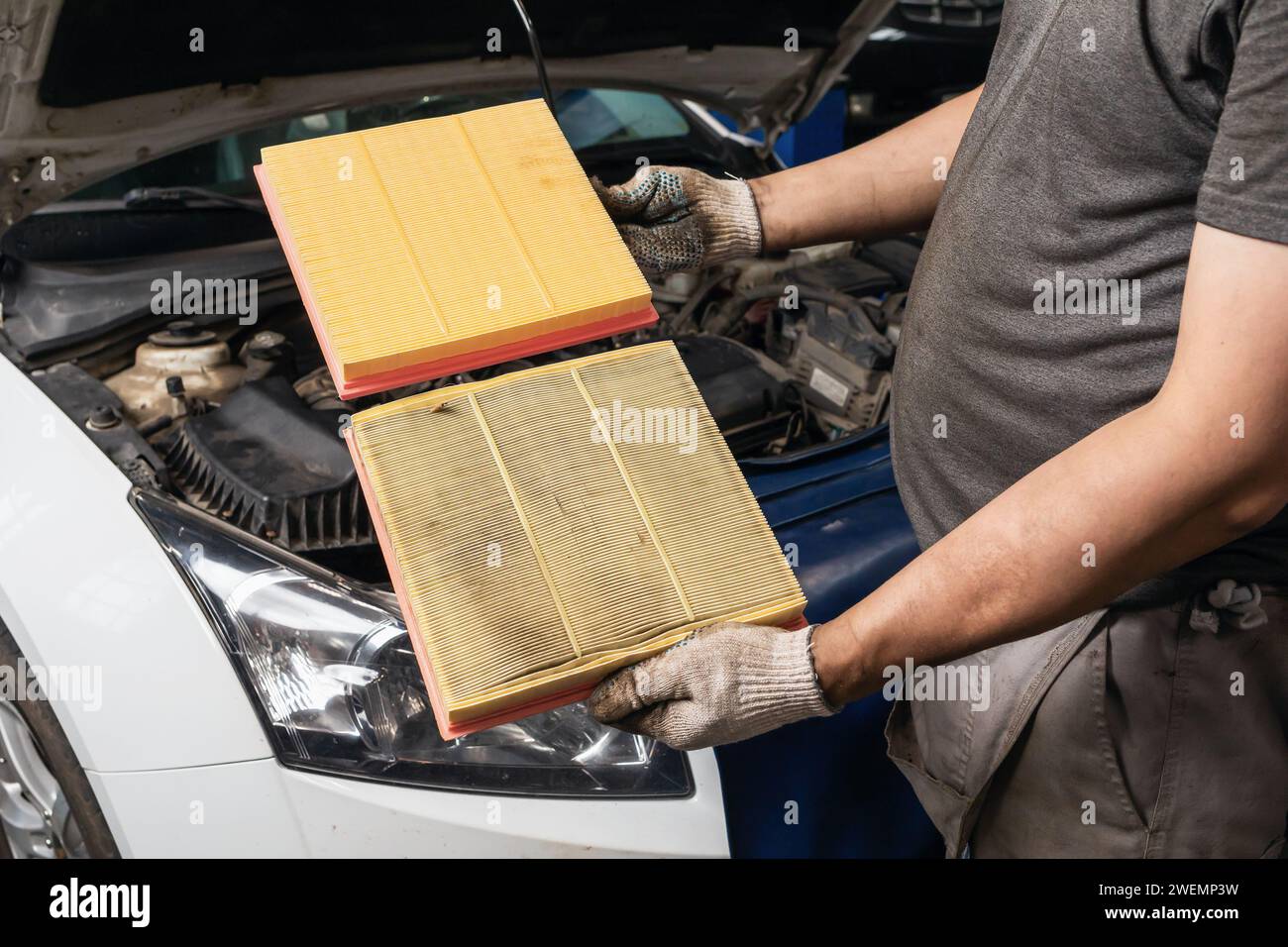 Auto mechanic shows old and new engine air filter for a passenger car ...