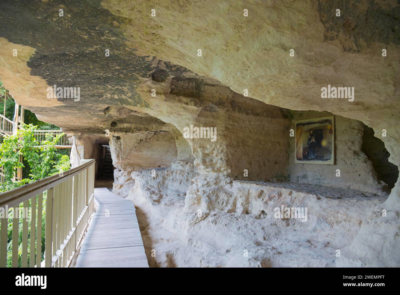 Path with railing leads to a cave dwelling surrounded by vegetation ...