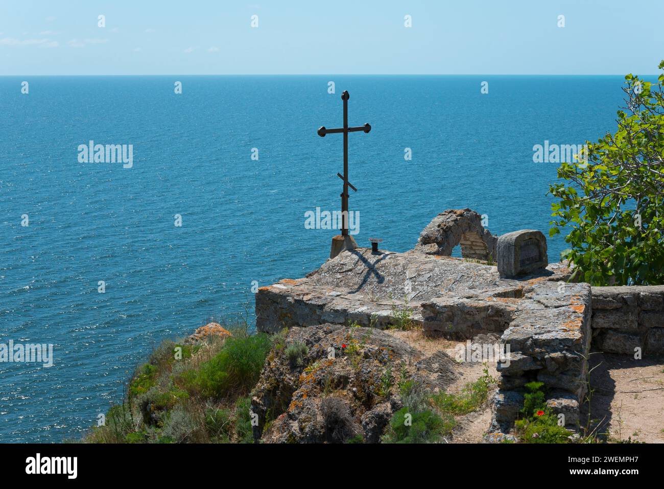 A simple cross overlooks the calm sea from a rocky cliff, Chapel of St ...