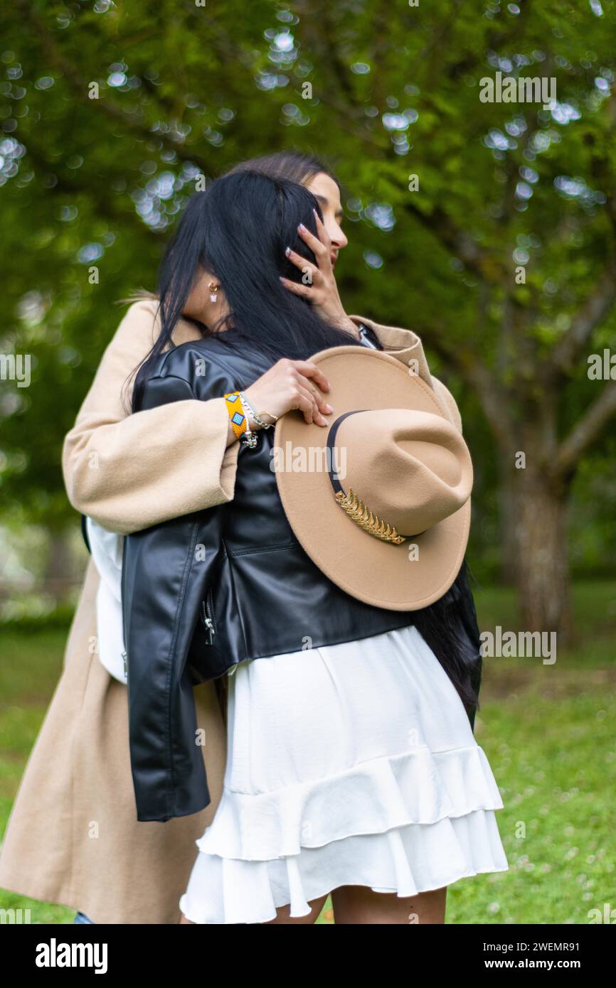 Portrait of two female friends standing hugging on the grass, Rear view ...