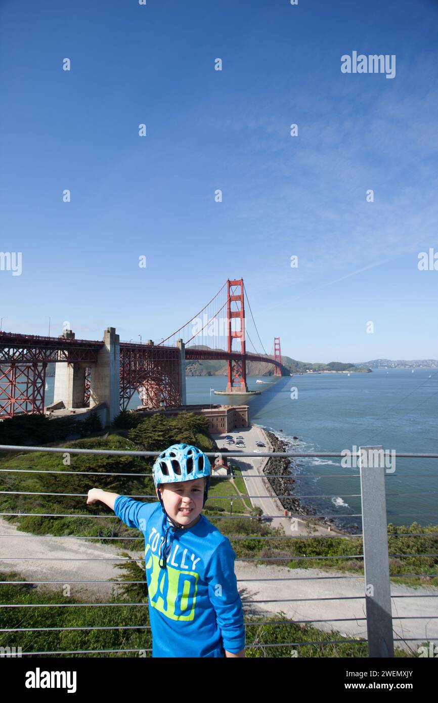 Young boy wearing a bicycle helmet pointing at the Golden Gate ...