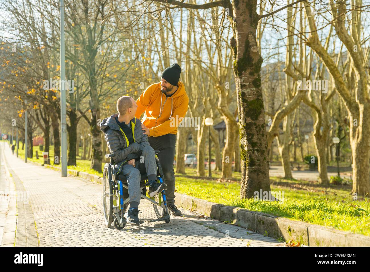 Man pushing the wheelchair of a disabled friend along the path of a ...