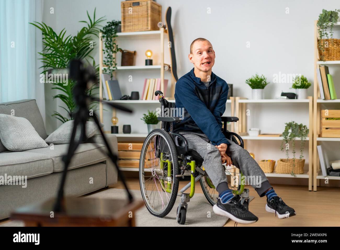 Disabled man in wheelchair recording vlog using digital camera at home ...