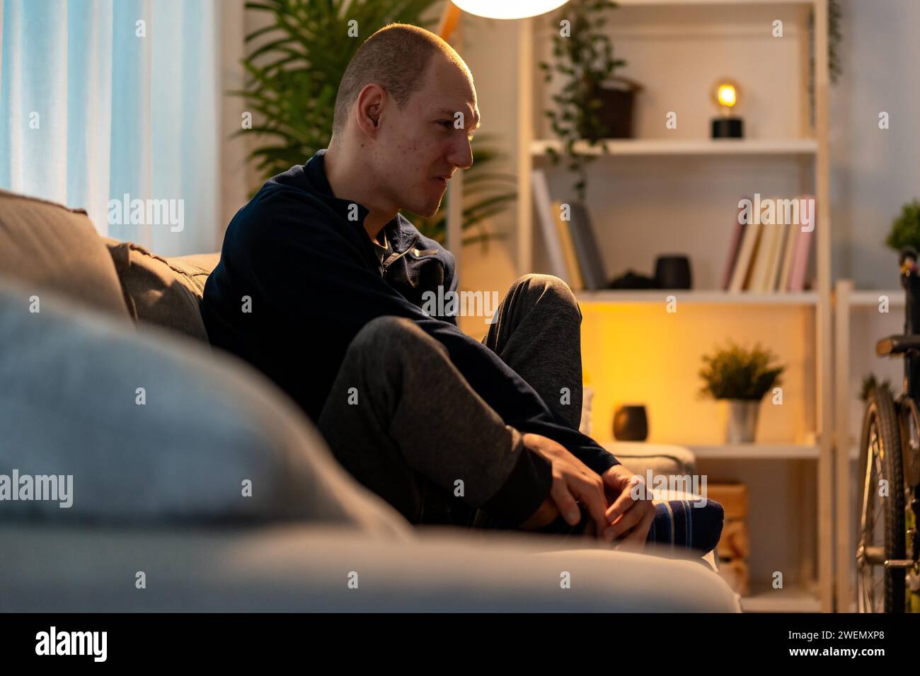 Disabled man sitting alone in the sofa with sad expression in the night ...
