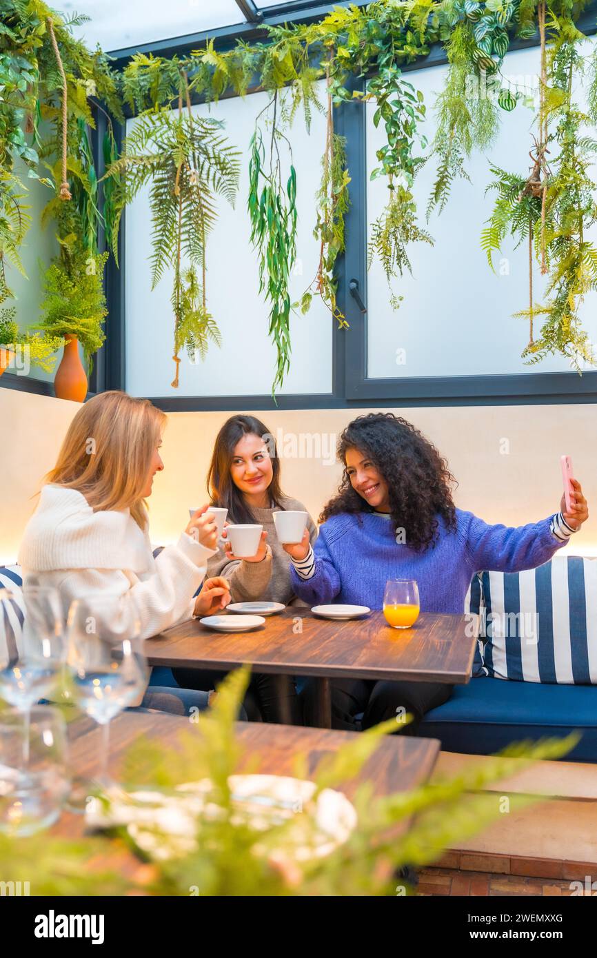 Vertical photo with copy space of three women taking selfie sitting ...