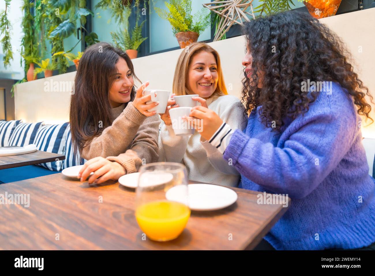Three adult caucasian women talking happily in a colorful cafeteria ...