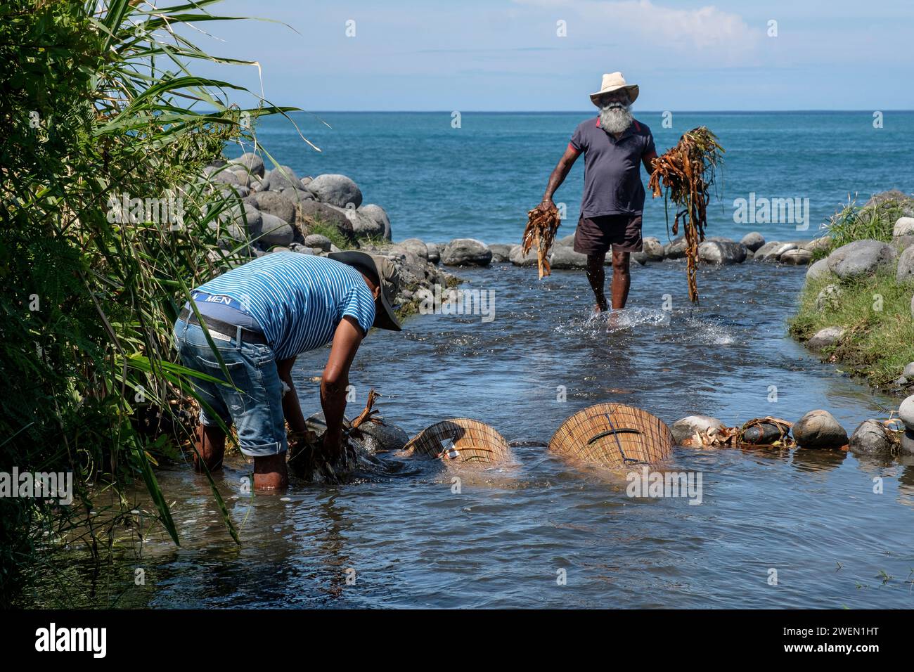 Two fishermen stand in Riviere Saint Etienne while using a traditional ...