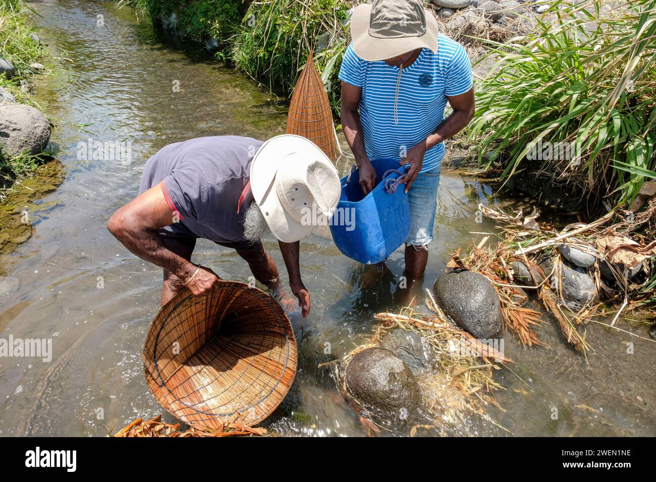 Two fishermen stand side by side in river Saint Etienne on Reunion ...