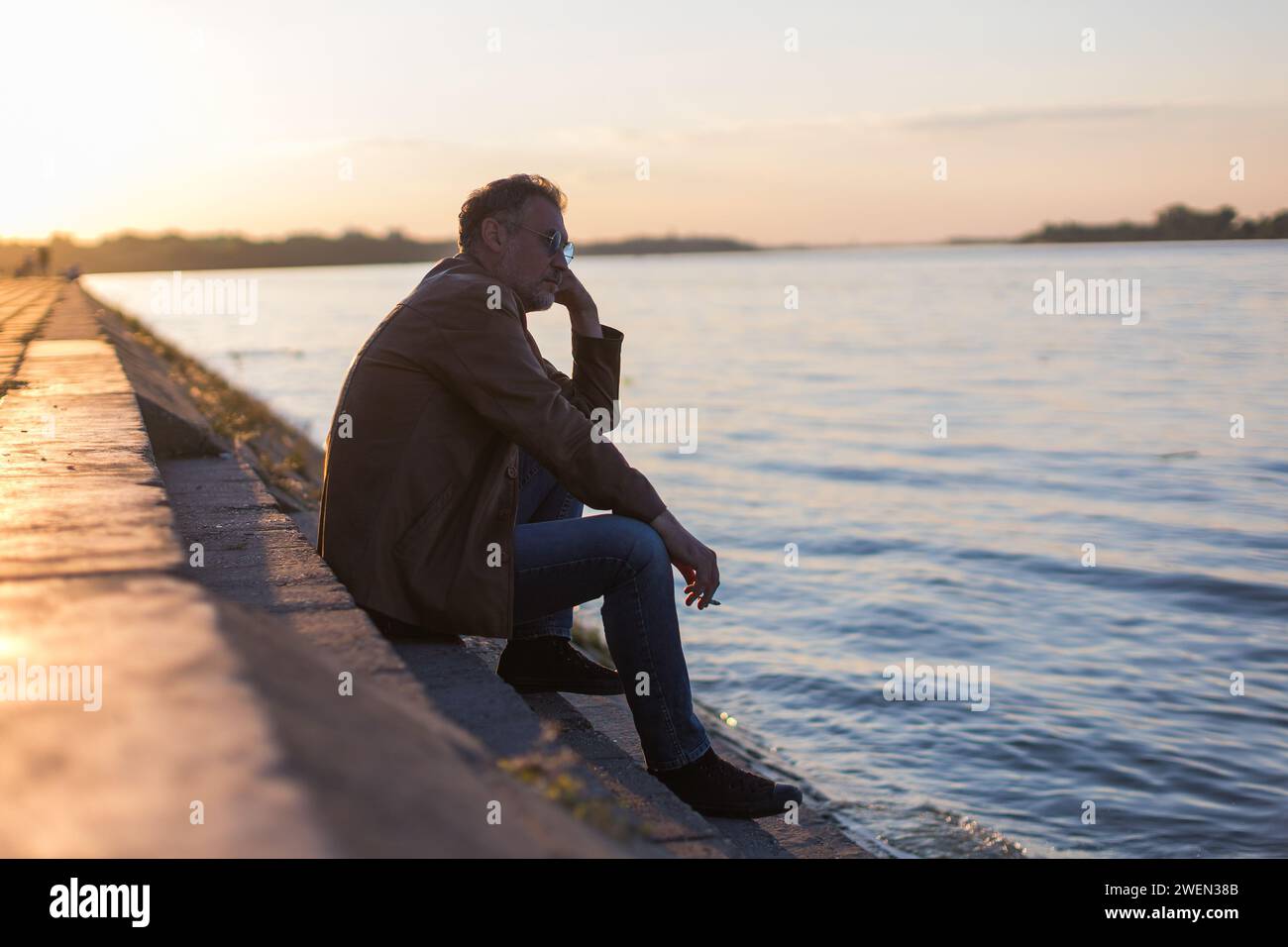 lonely man sitting on stairs next to the river bank Stock Photo - Alamy