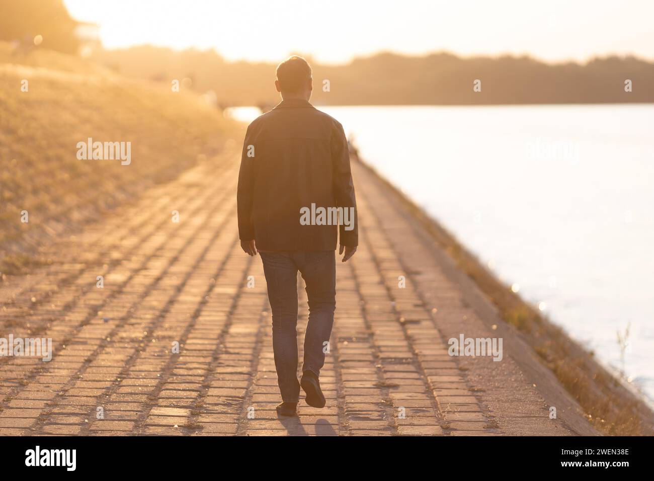 single man walking away into sunset Stock Photo - Alamy