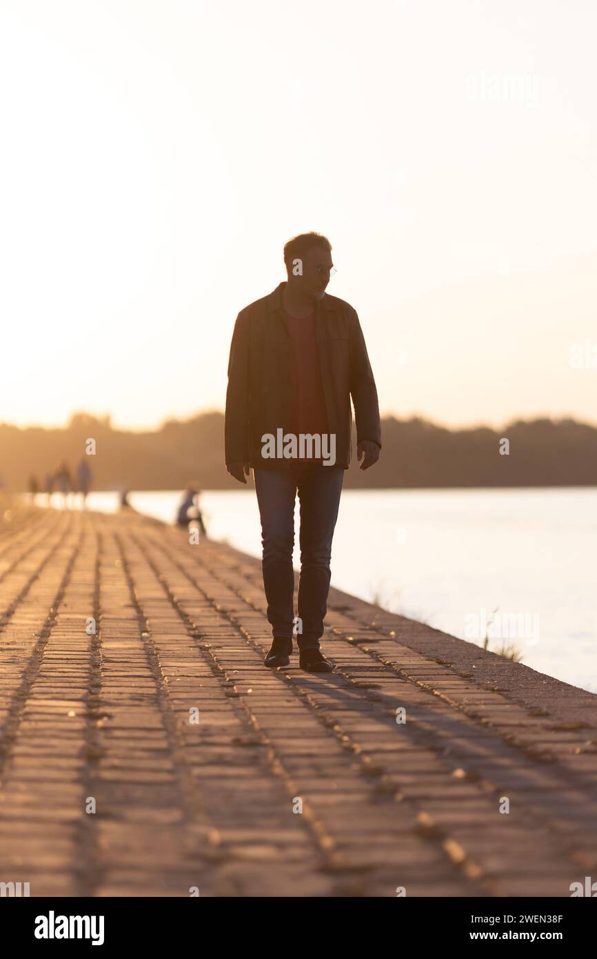 single man walking on river edge Stock Photo - Alamy