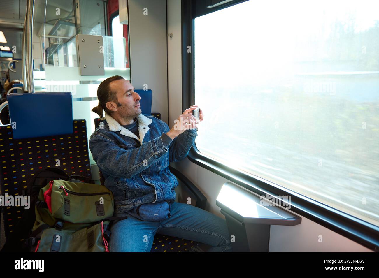 Cheerful young adult Caucasian man in casual denim, gazing out the ...