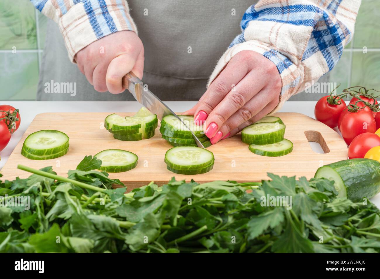 Women's hands chop cucumbers for vegetable salad with a knife. Copy ...