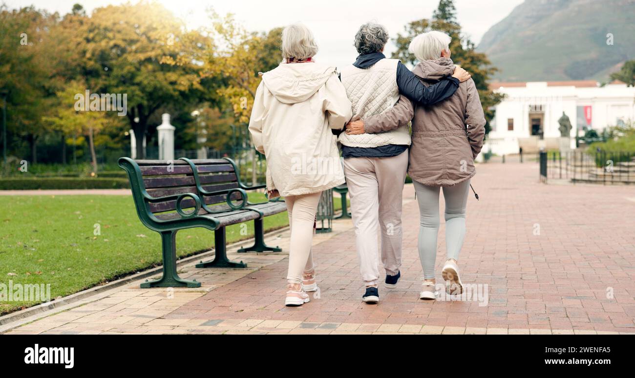 Senior friends, talking and walking together on an outdoor path to ...